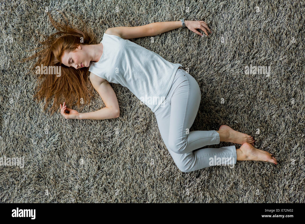 Young woman laying on the carpet Stock Photo - Alamy