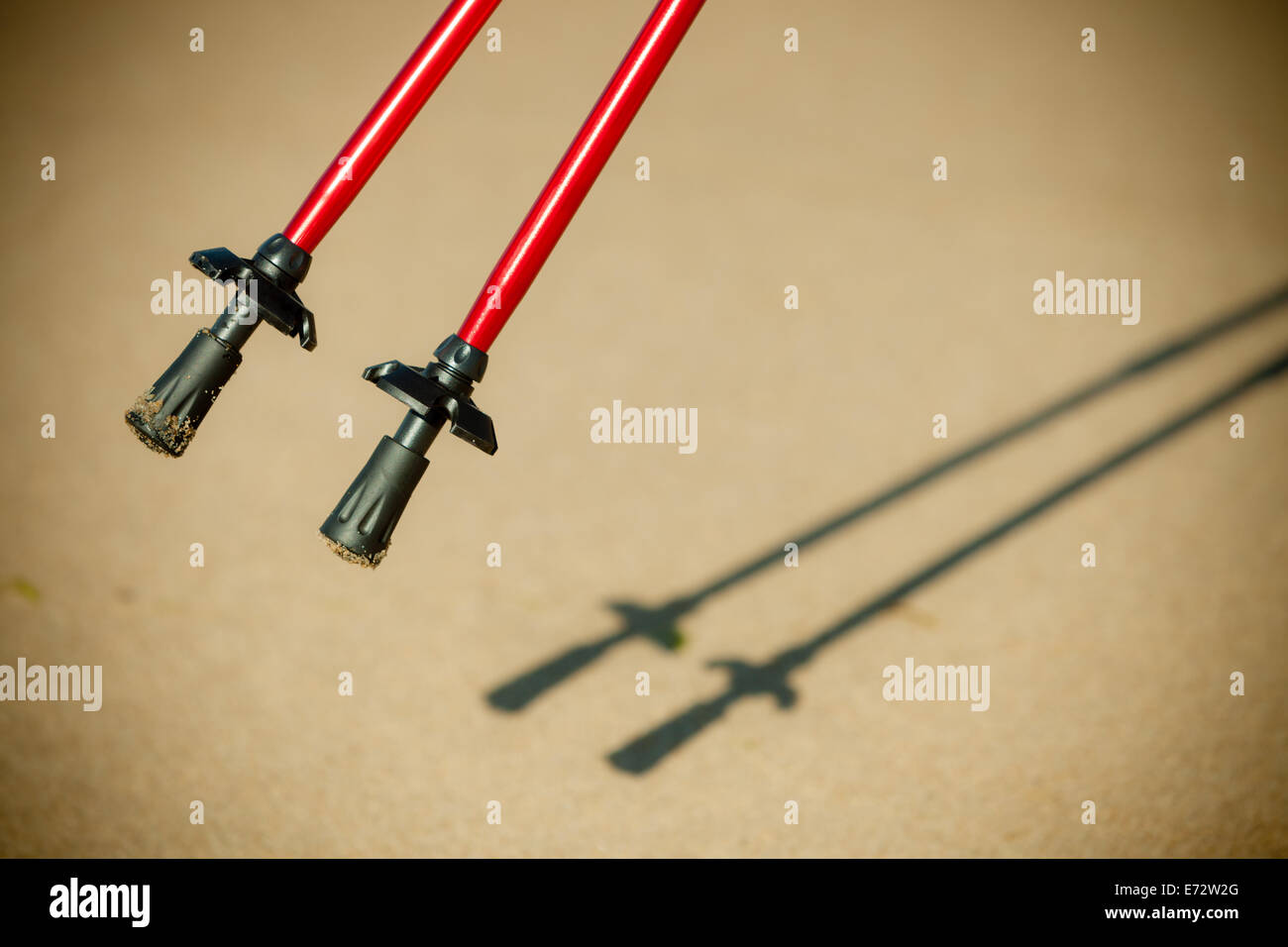 Nordic walking equipment. Closeup of red sticks on the sandy beach ...