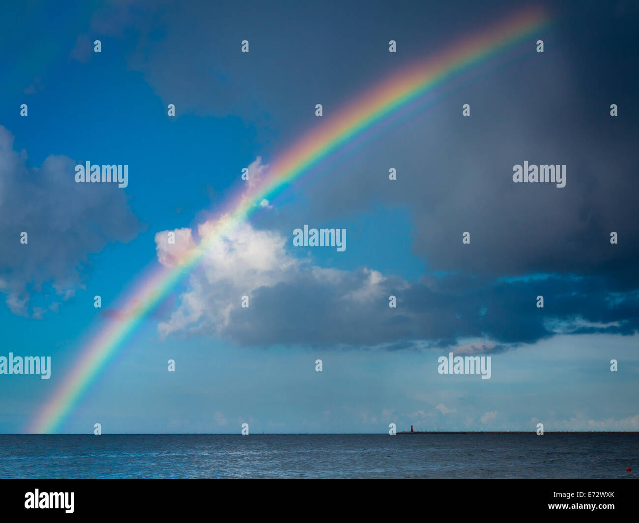 landscape view on cloudy sky with colorful rainbow at sea or ocean ...