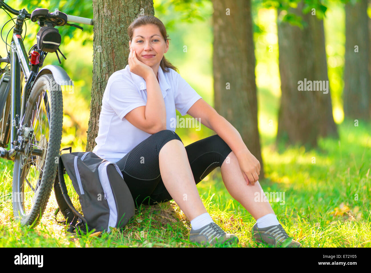 tired cyclist resting in a park near a tree Stock Photo - Alamy