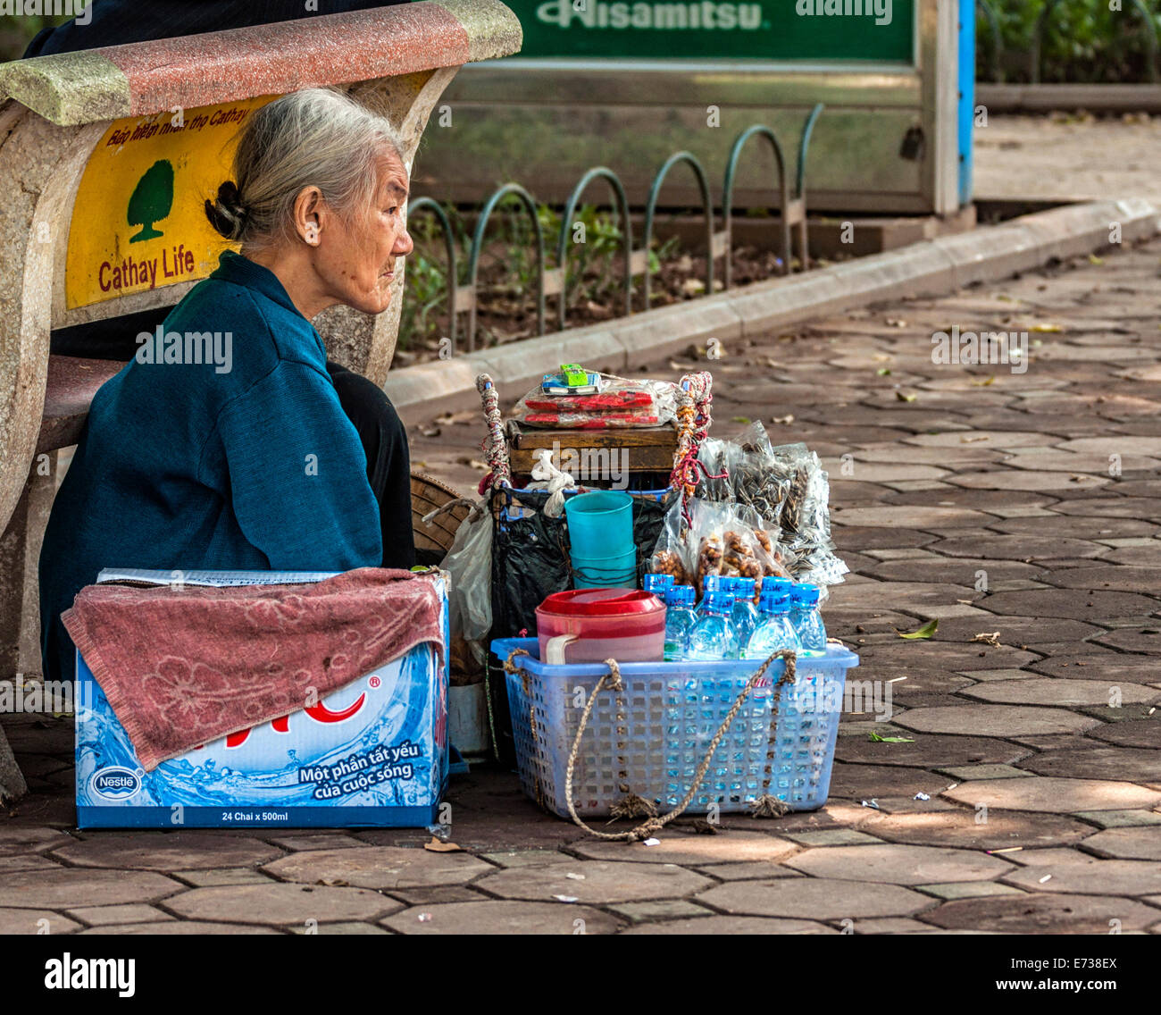 Old woman street vendor selling water while sitting on her haunches ...
