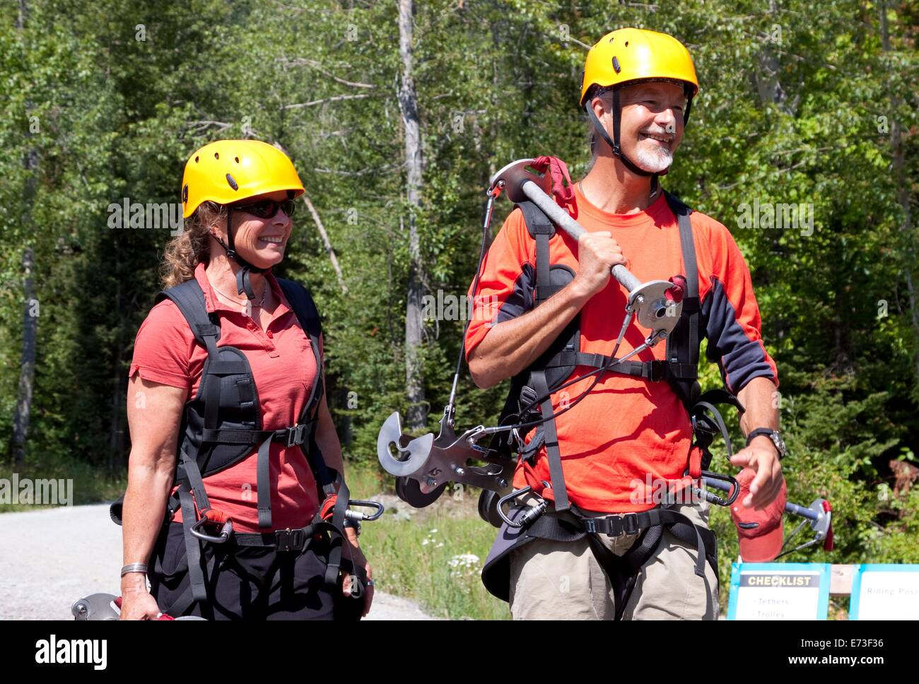 Two people about to ride a zip line Stock Photo - Alamy