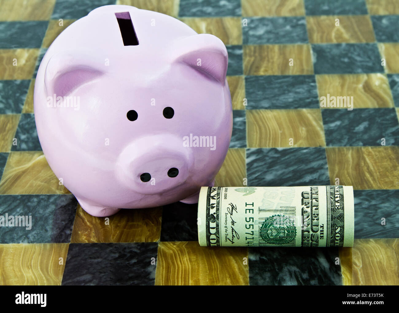 Pink savings bank with rolled American dollar placed on game board ...