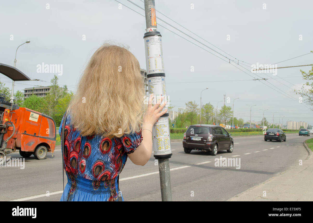 blonde woman with blue dress and the bus ride schedule stanchion Stock ...