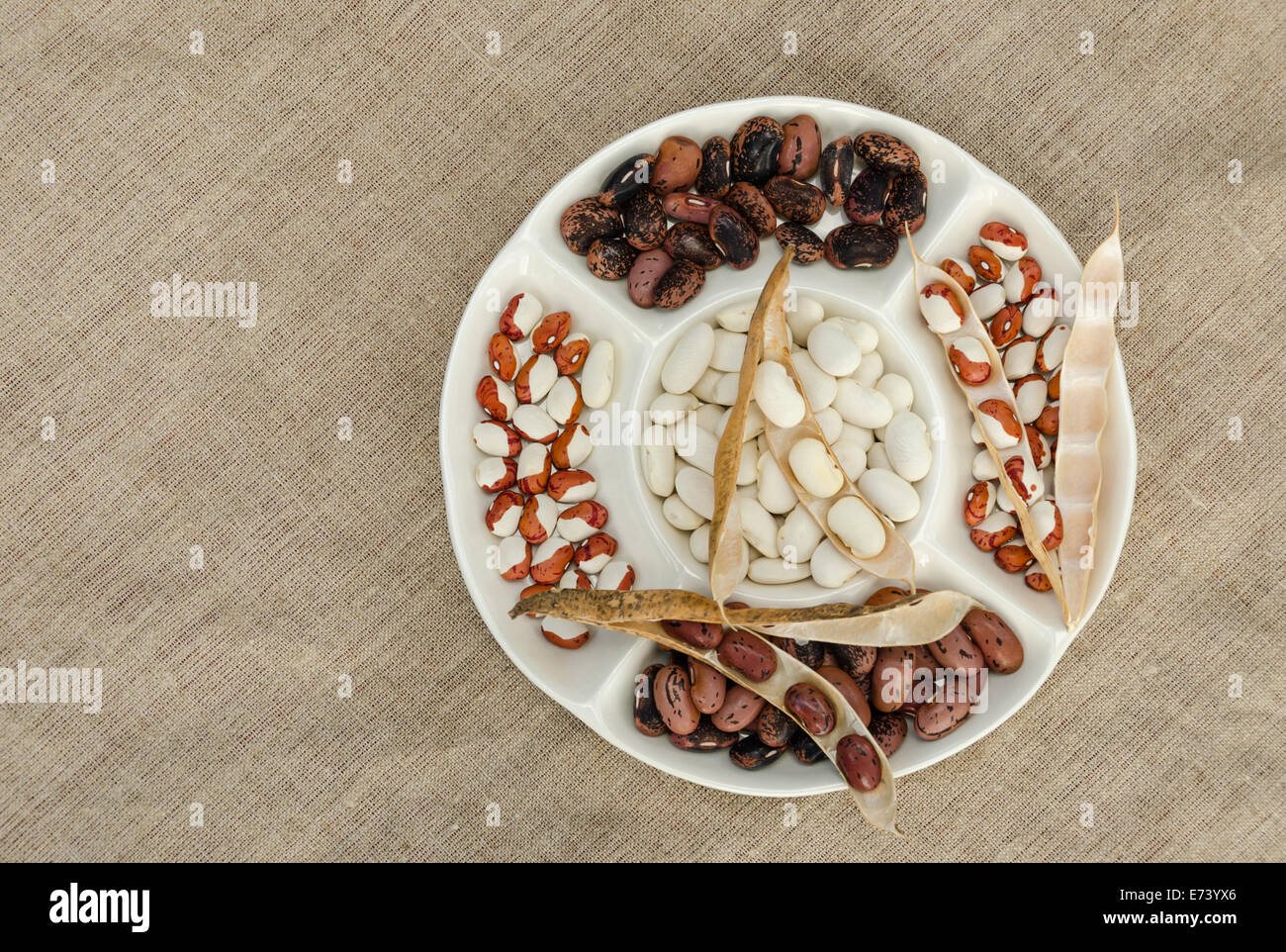 dried colorful winter beans mix in white plate on linen texture ...
