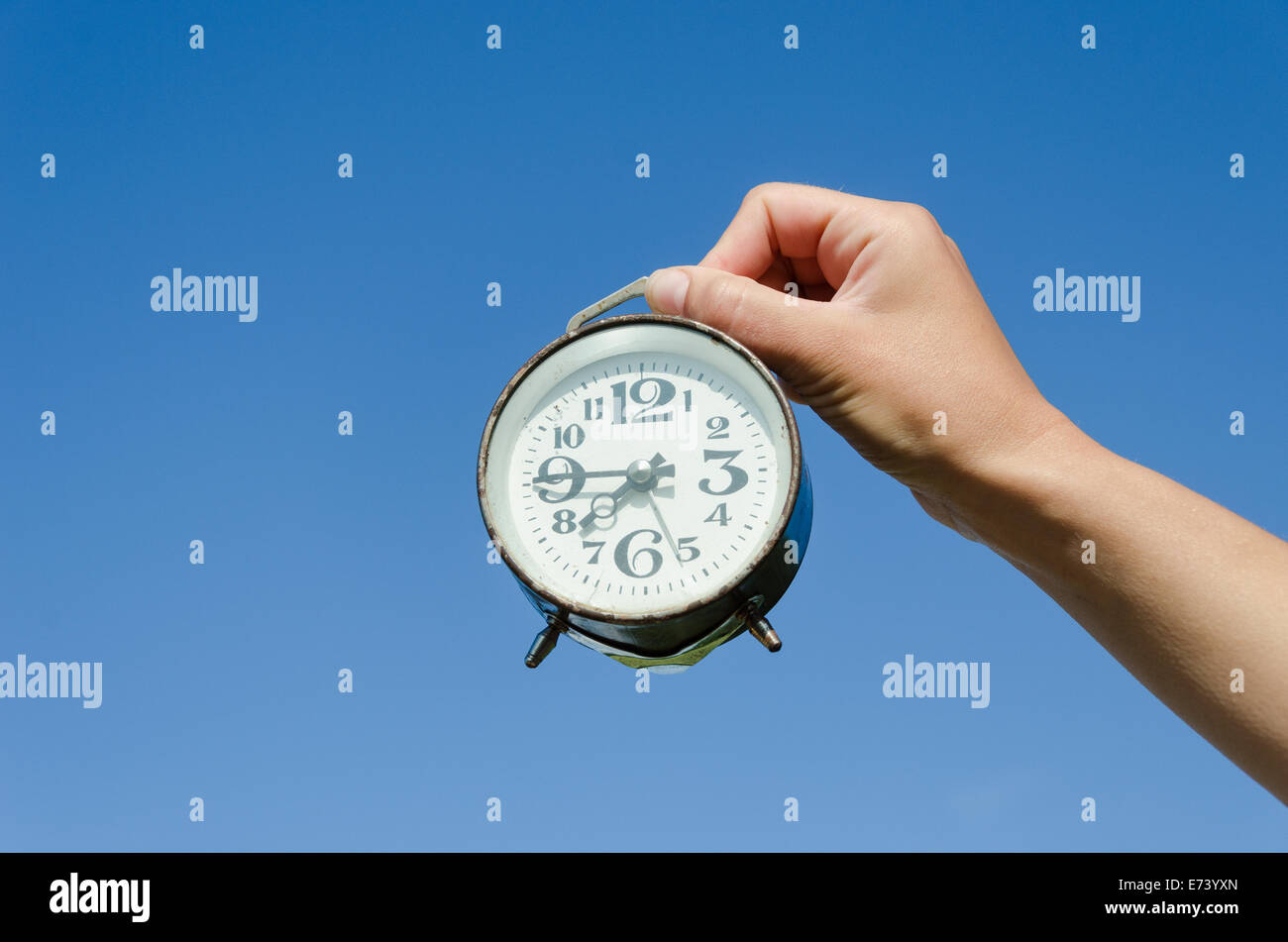 girl hand hold small old retro alarm clock with large black numerals on ...