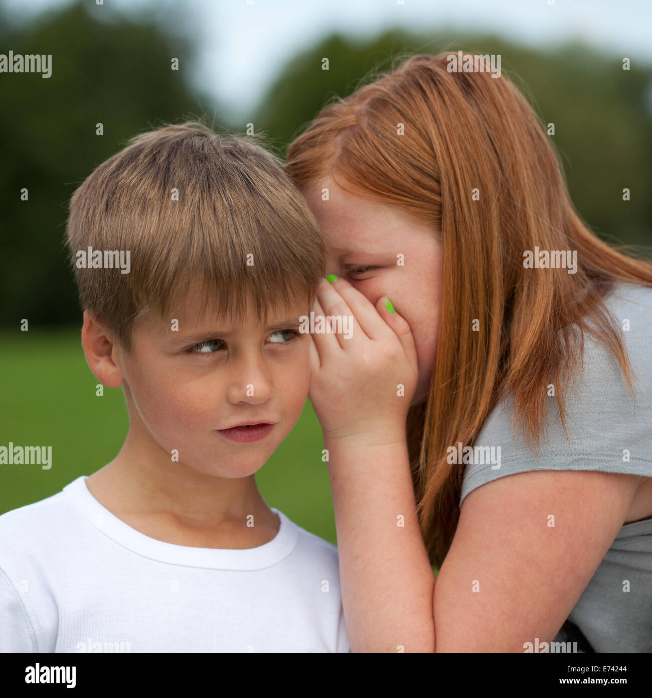 Girl whispering into boys ear hi-res stock photography and images - Alamy