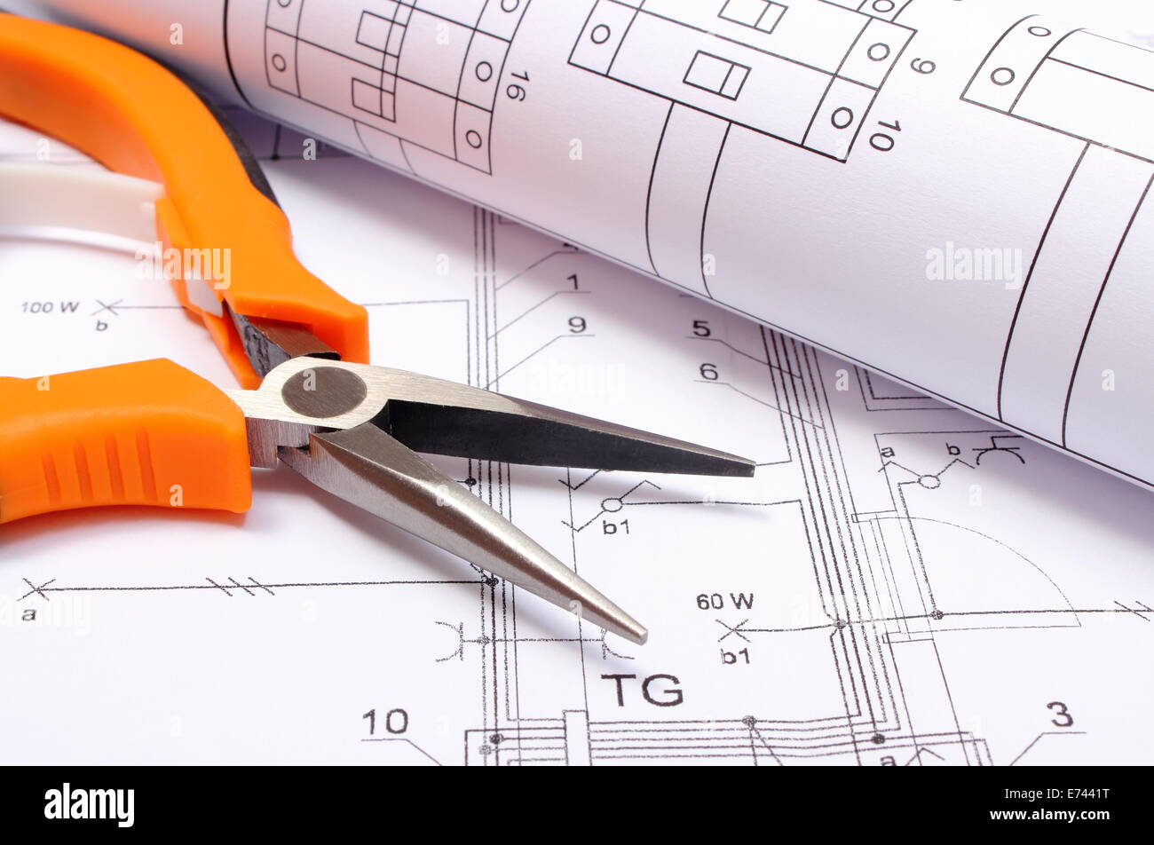 Orange metal pliers with rolled electrical diagram lying on ...