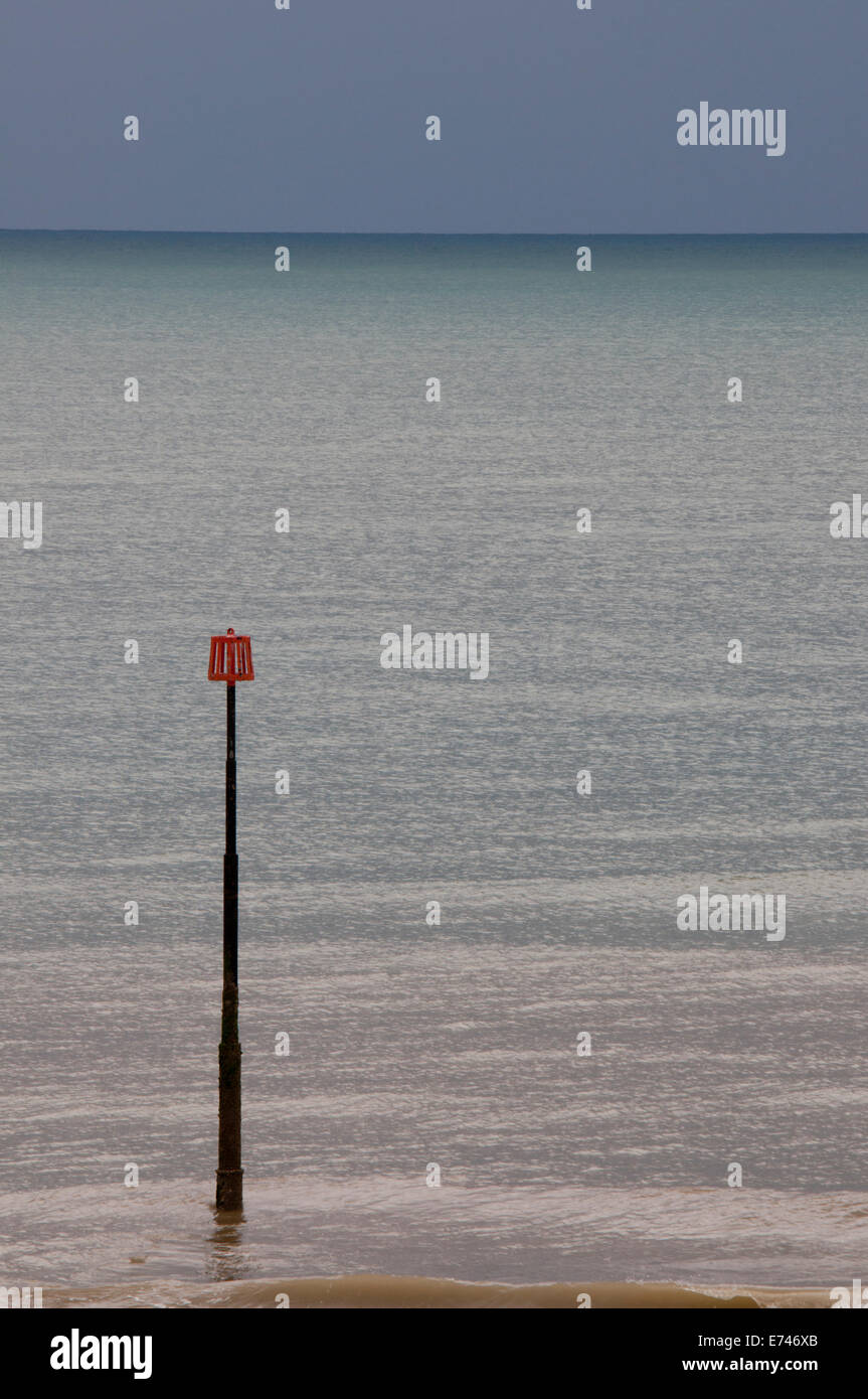 A groyne marker at high tide against a background of a calm sea at ...