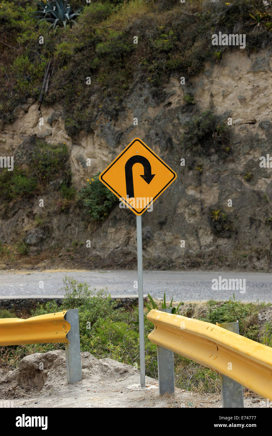 A roadside sign indicating a sharp turn ahead on a road in Cotacachi ...