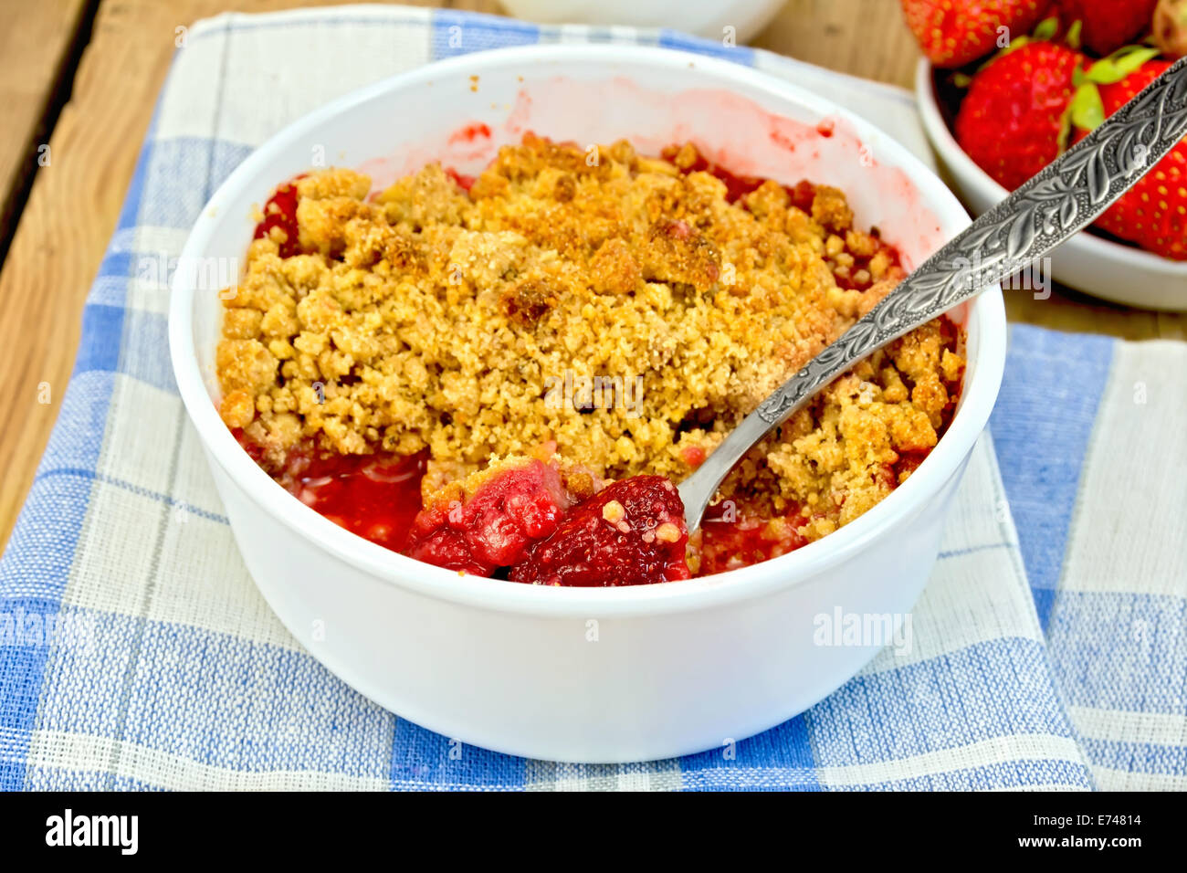 Strawberry crumble in a white bowl with a spoon on a napkin ...