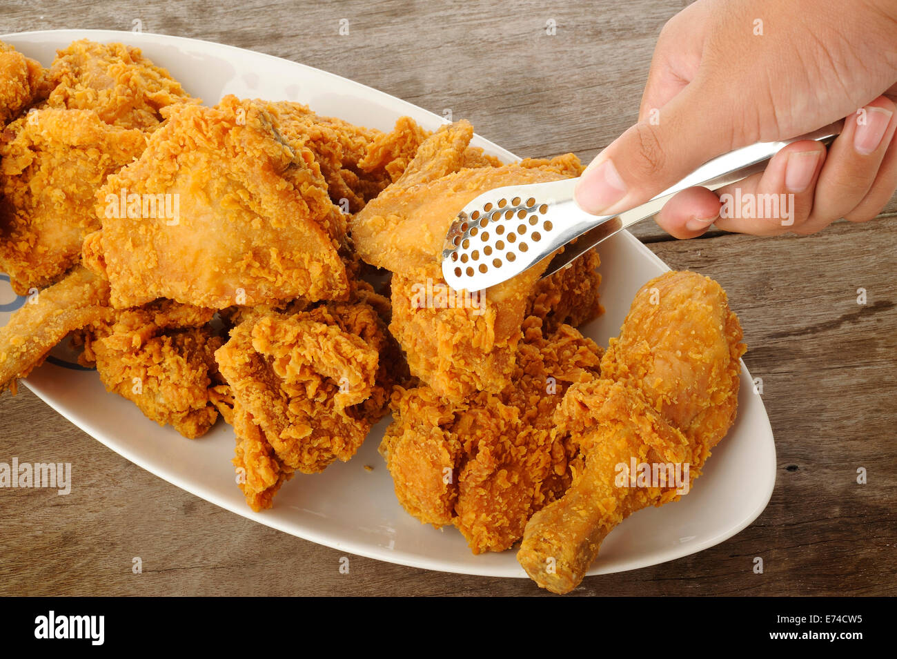 Tongs holding fried chicken Stock Photo - Alamy