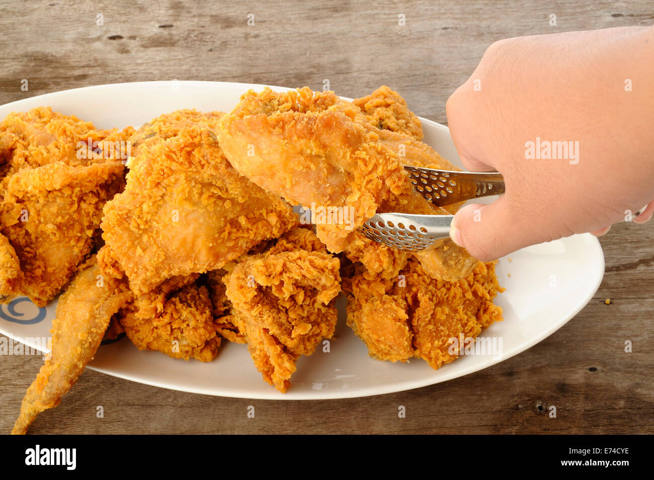 Tongs holding fried chicken Stock Photo - Alamy