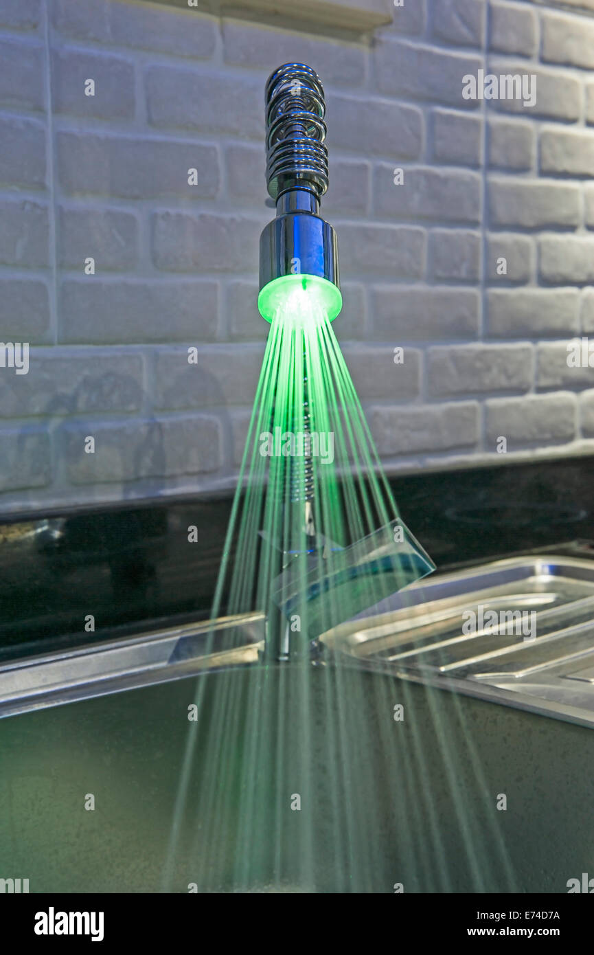 Ornate illuminated luxury tap faucet with green light and water running ...