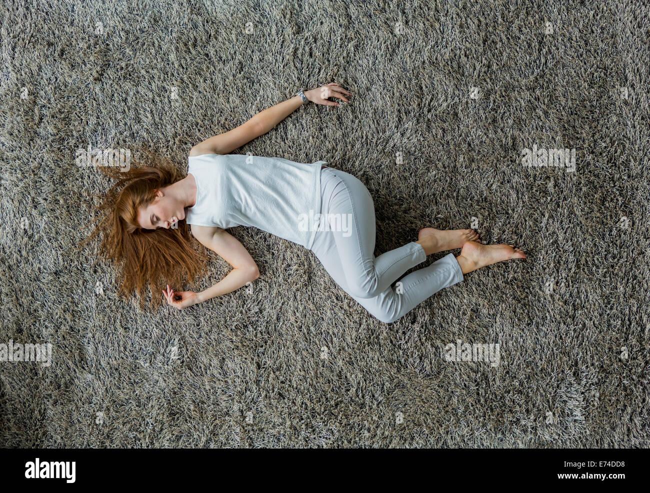 Young woman laying on the carpet Stock Photo - Alamy
