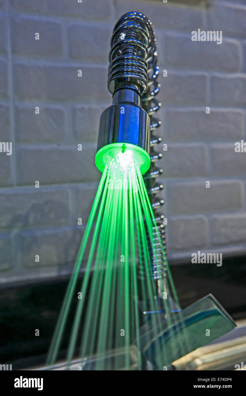 Ornate illuminated luxury tap faucet with green light and water running ...