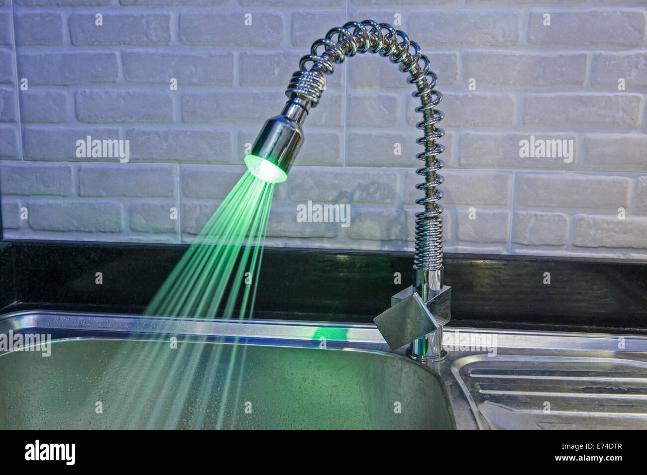 Ornate illuminated luxury tap faucet with green light and water running ...