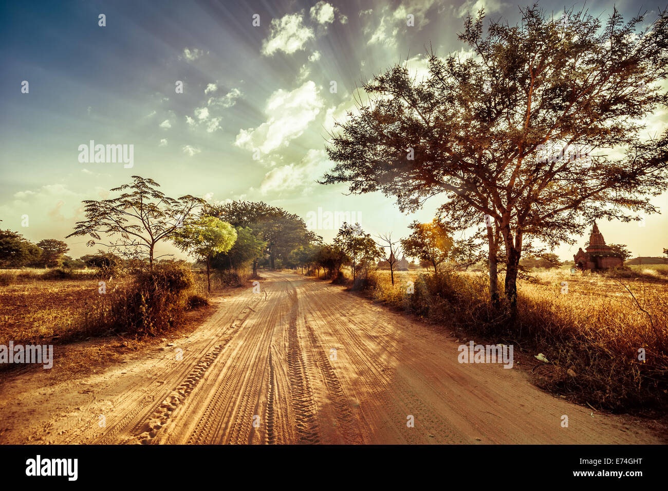 Empty road going through rural landscape under sunset sky with sun ...