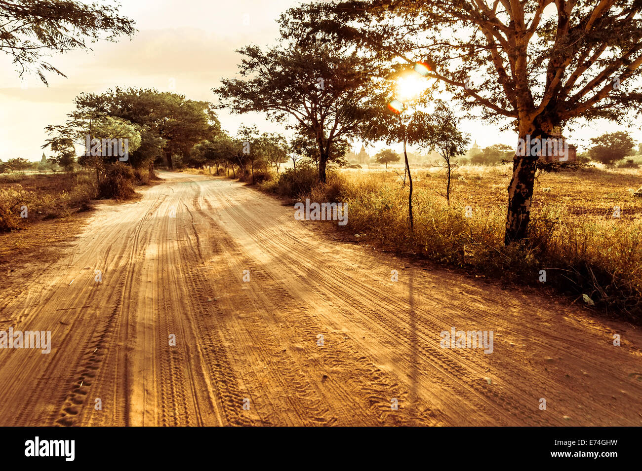 Empty road going through rural landscape under sunset sky with sun ...