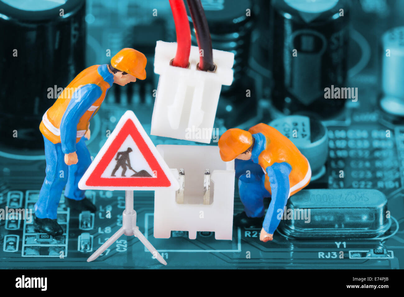 Miniature engineers fixing wire connector on circuit board. Computer ...