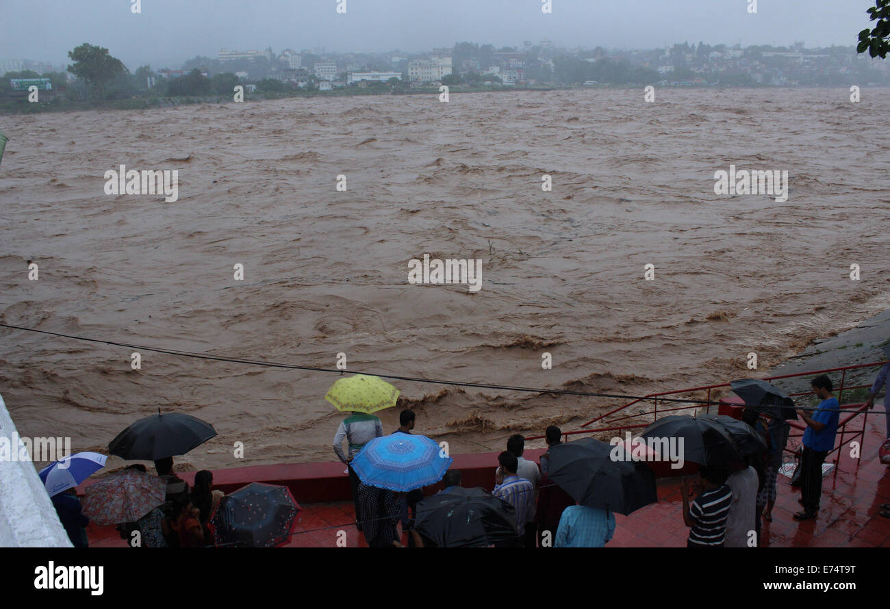 People watch the raging water of the Tawi river that caused a bridge to ...