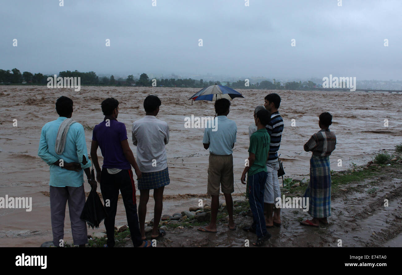 People watch the raging water of the Tawi river that caused a bridge to ...