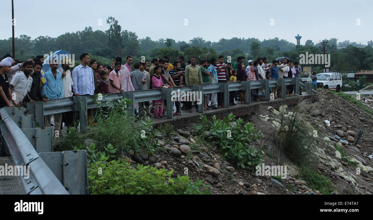 People watch the raging water of Tawi river that caused a bridge to ...