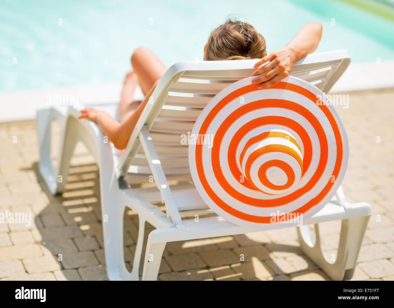 Young woman in hat laying on chaise-longue. rear view Stock Photo - Alamy