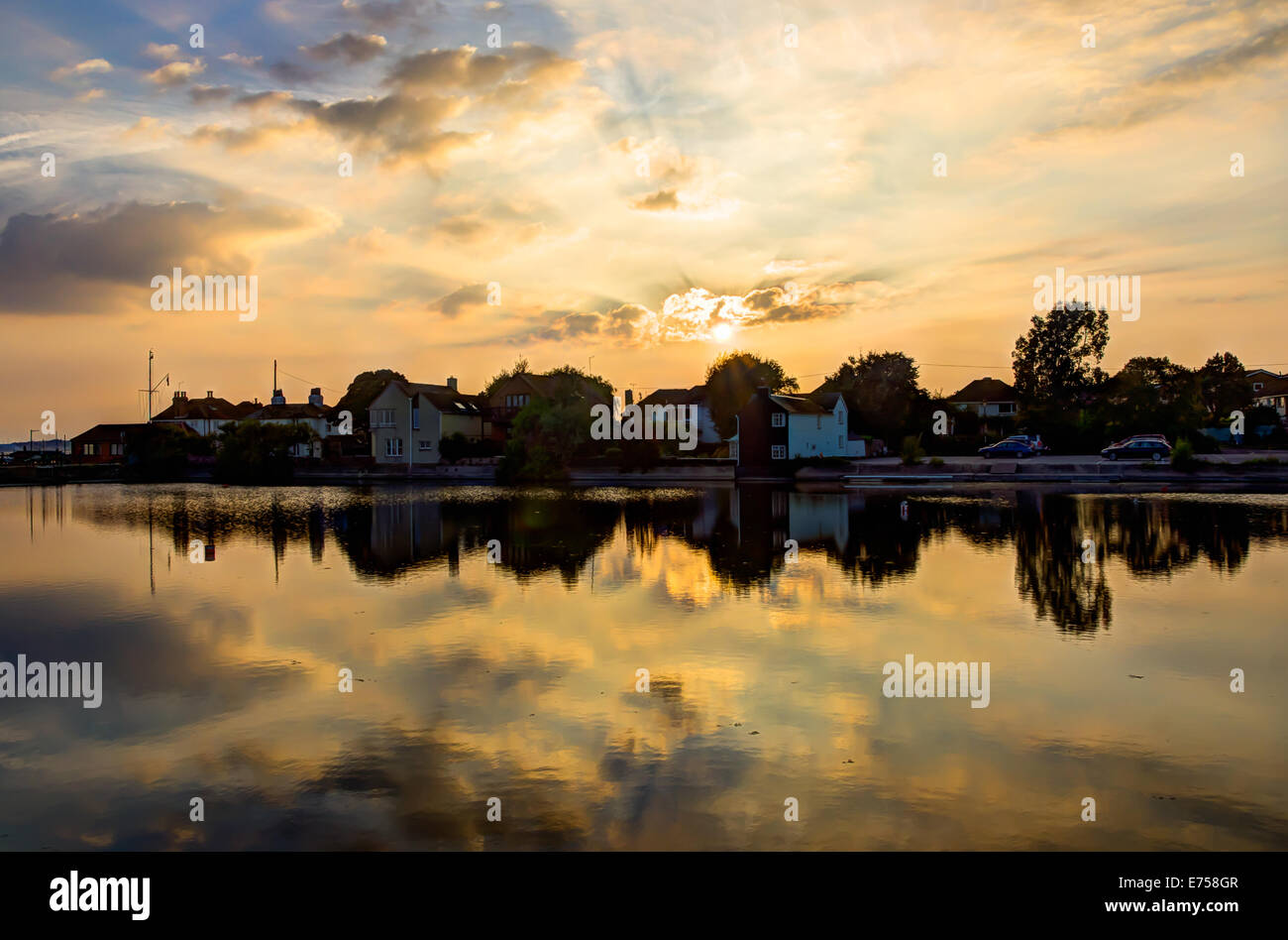Sunset behind houses being reflected in the lake Stock Photo - Alamy