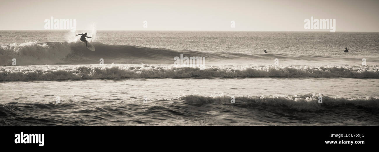 Surfer riding a long wave with spray rising up from the ocean Stock ...