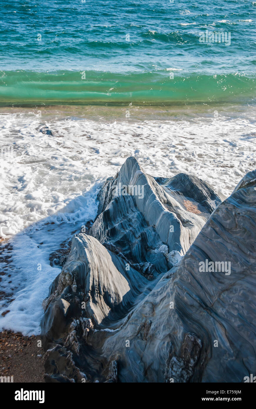Waves eroding a peninsular of rocks pointing out to sea Stock Photo - Alamy