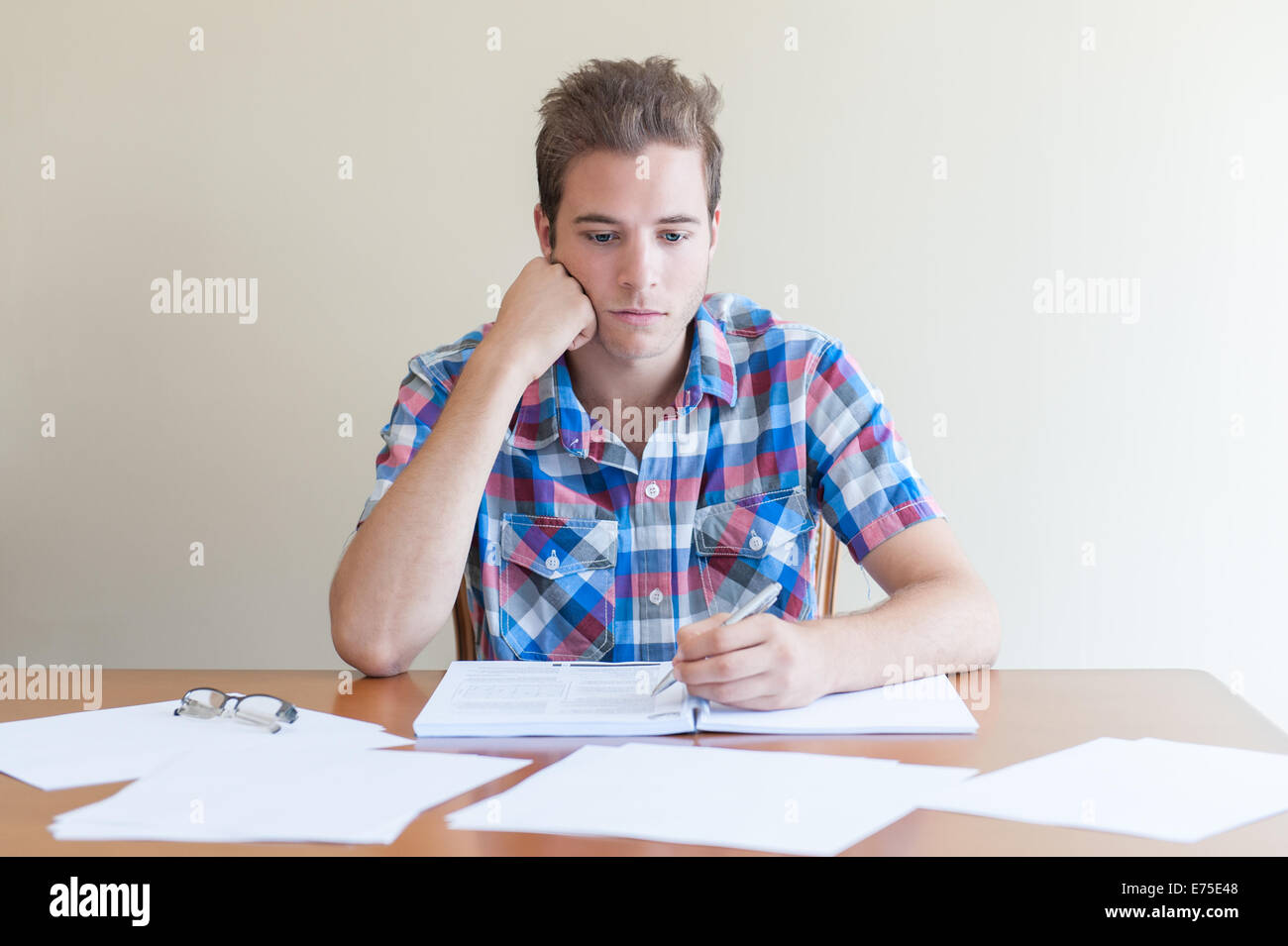 Young adult studying ,feeling frustrated, in a messy desktop. paper ...