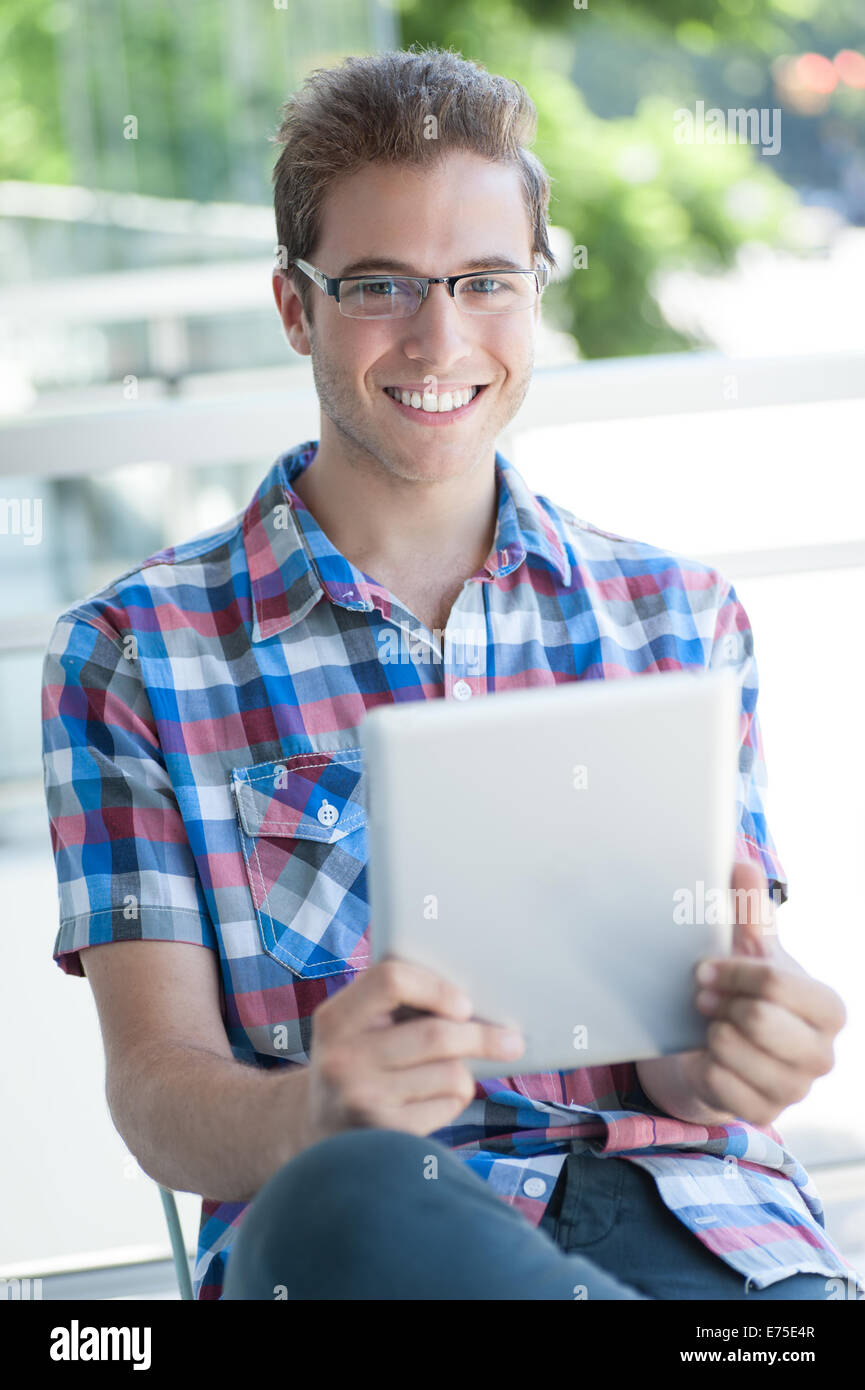 Young smiley male using a tablet pc looking at the camera Stock Photo ...