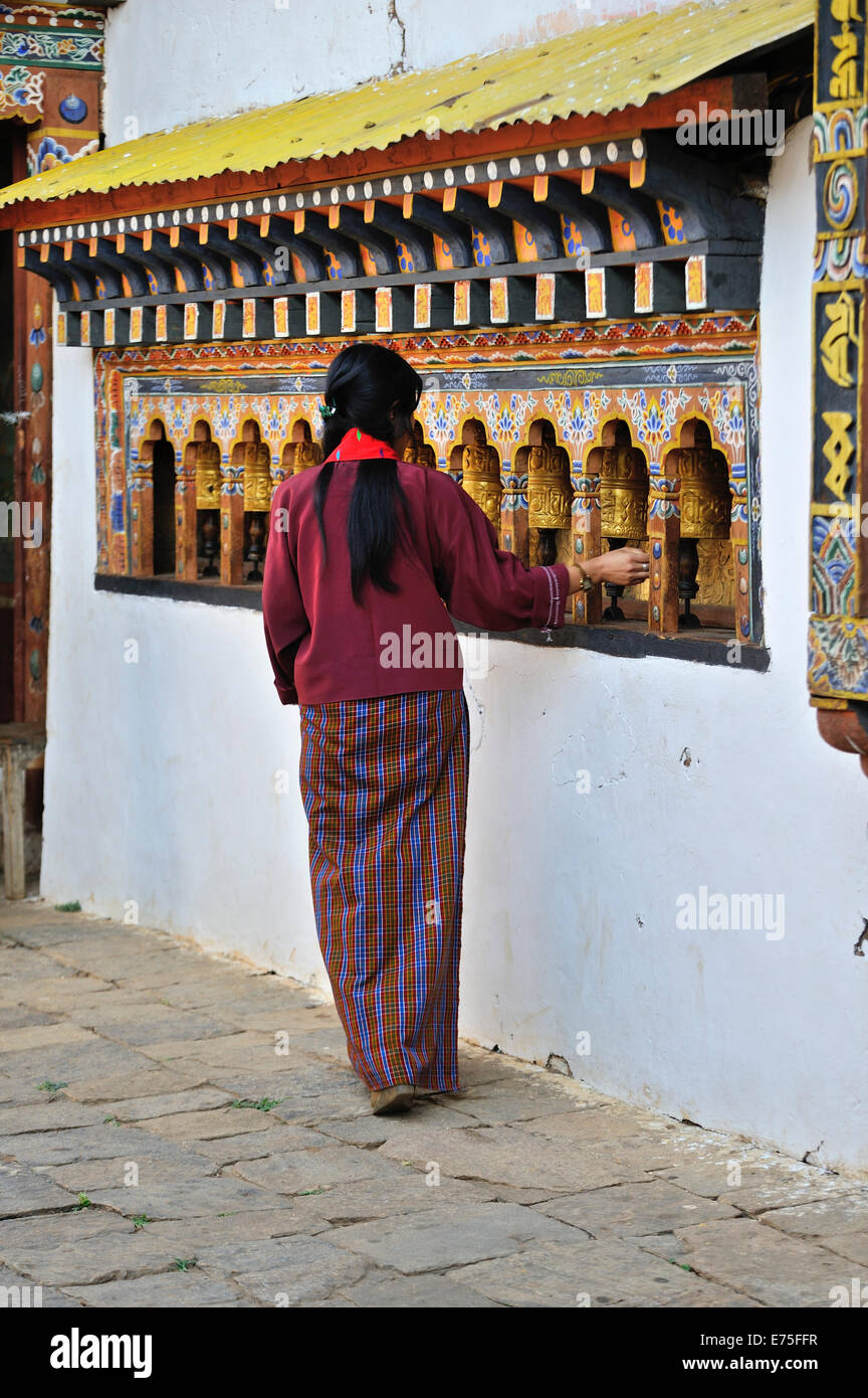 Young woman praying with the prayer wheels, Chime Lhakhang temple ...