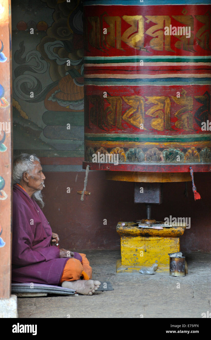 Buddhist man praying by the giant prayer wheel, Chime Lhakhang temple ...