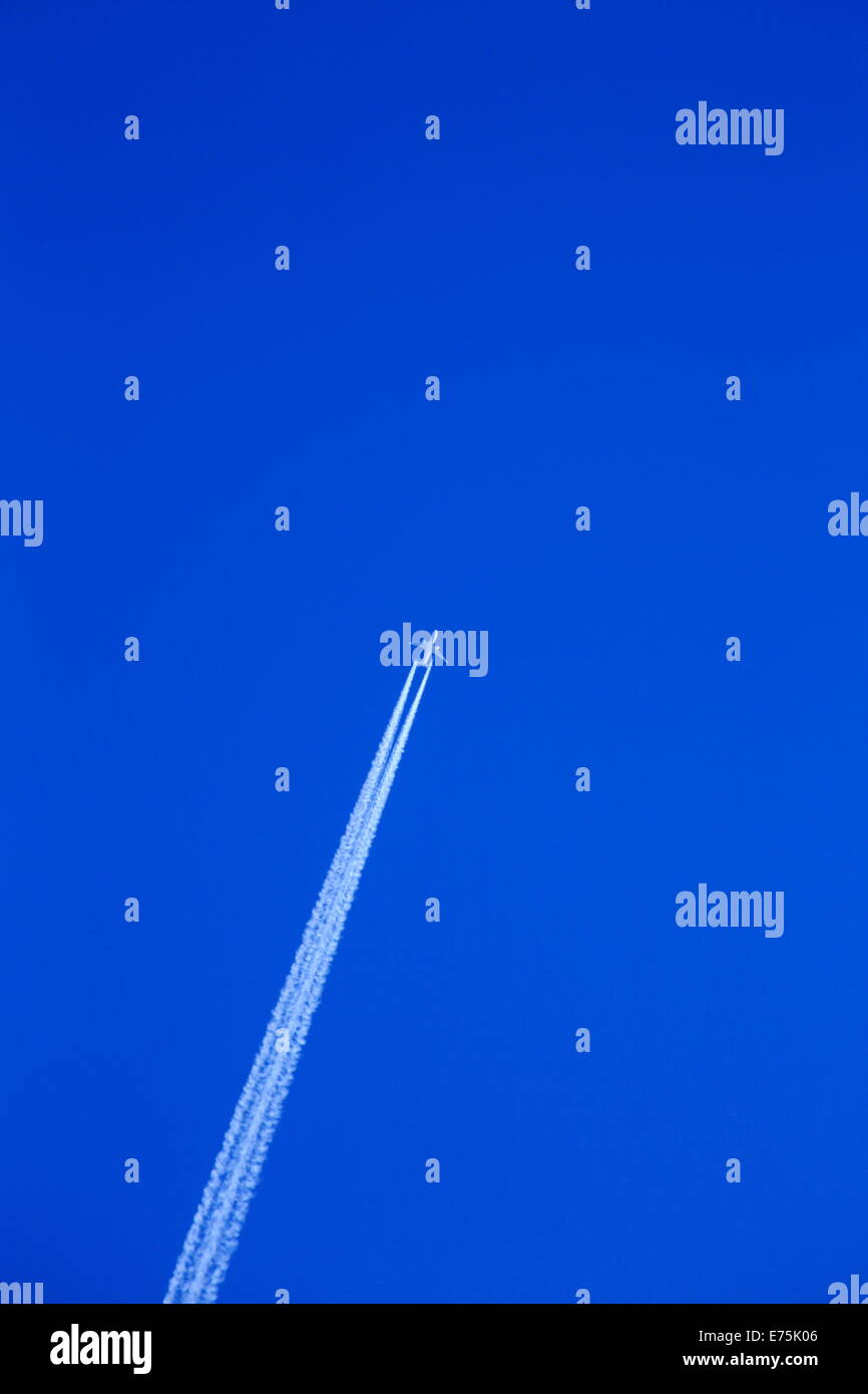An Airplane with contrail high in the sky Stock Photo - Alamy