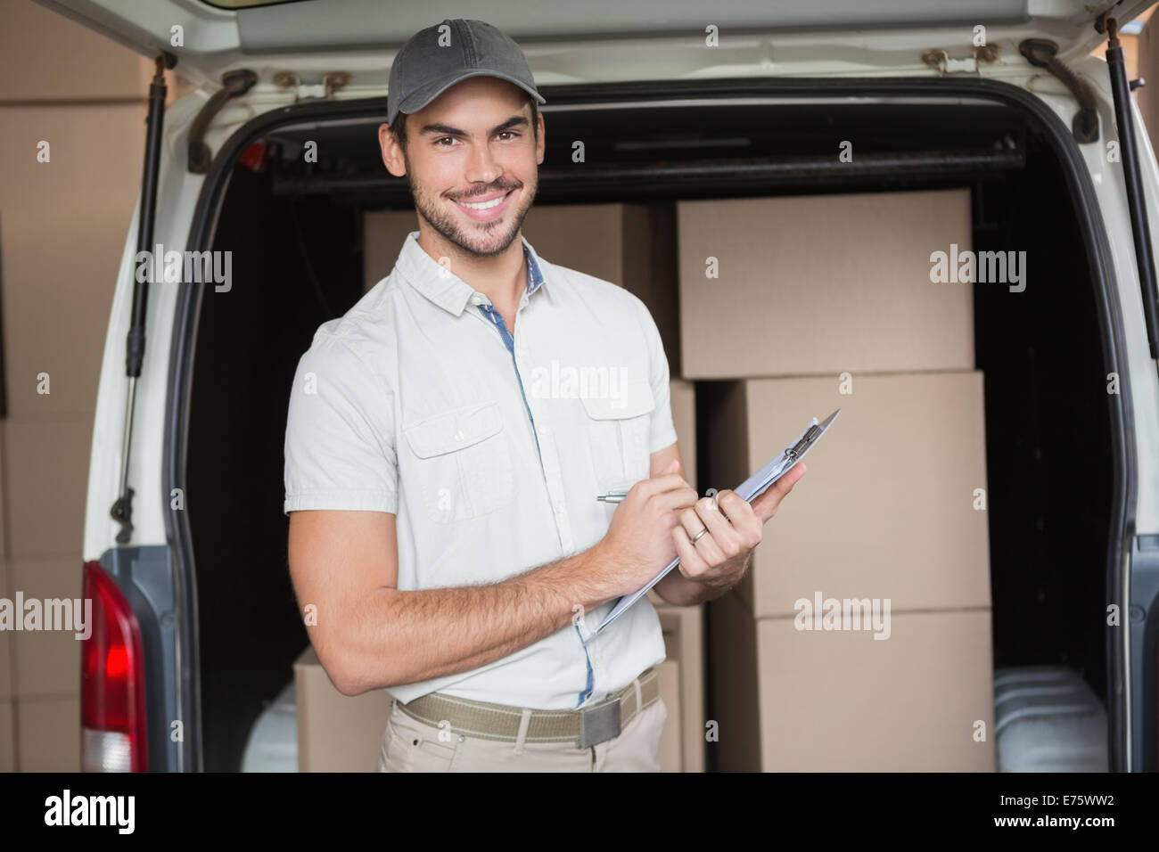 Delivery driver smiling at camera beside his van Stock Photo - Alamy
