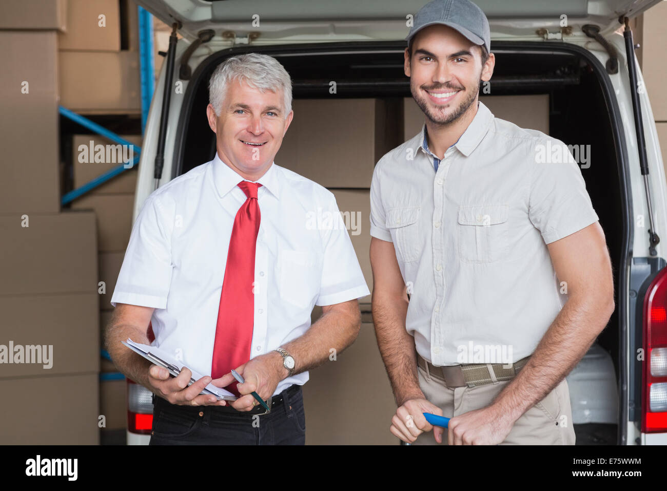 Warehouse manager and delivery driver smiling at camera Stock Photo - Alamy