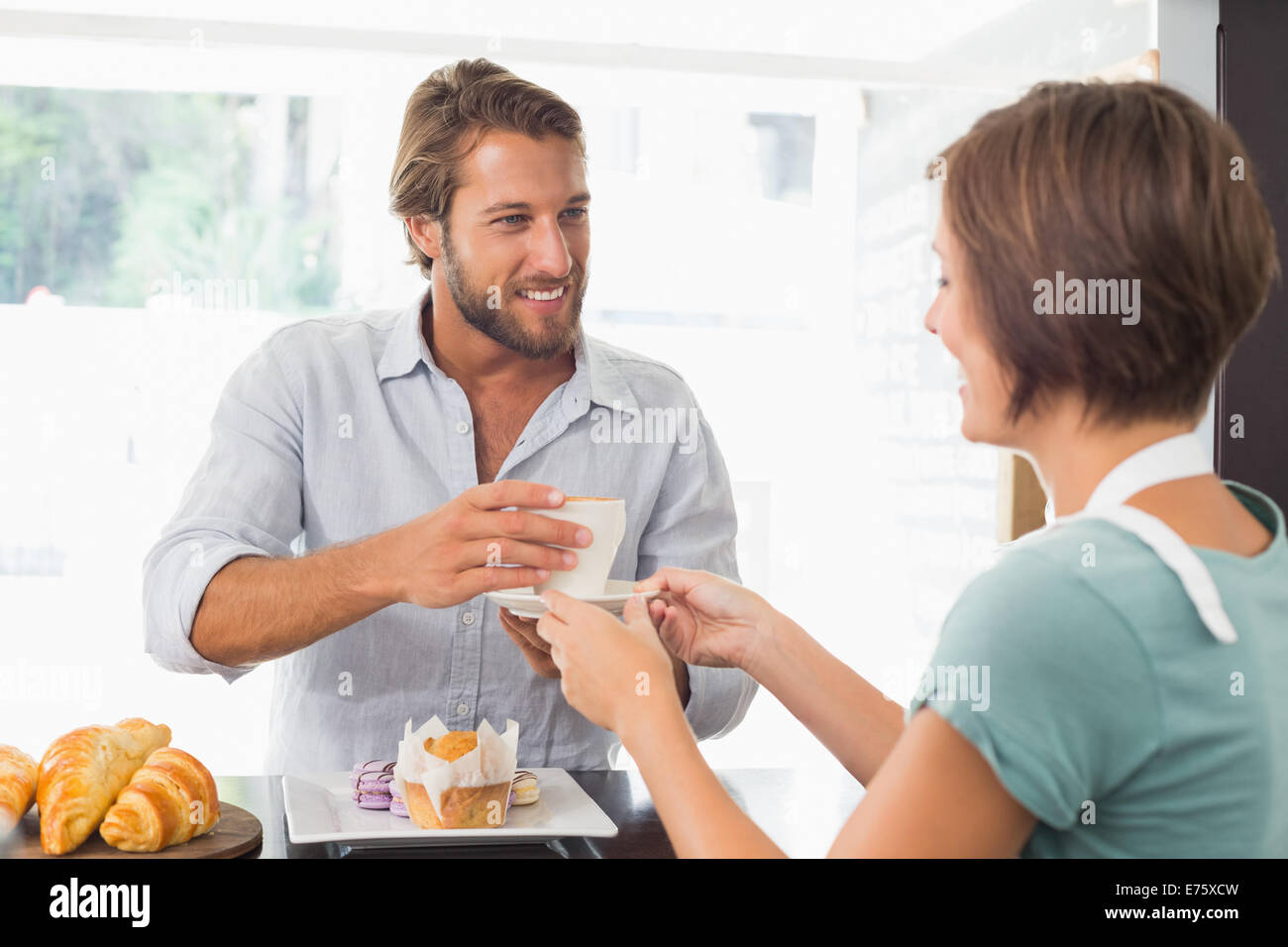 Pretty barista serving happy customer Stock Photo - Alamy