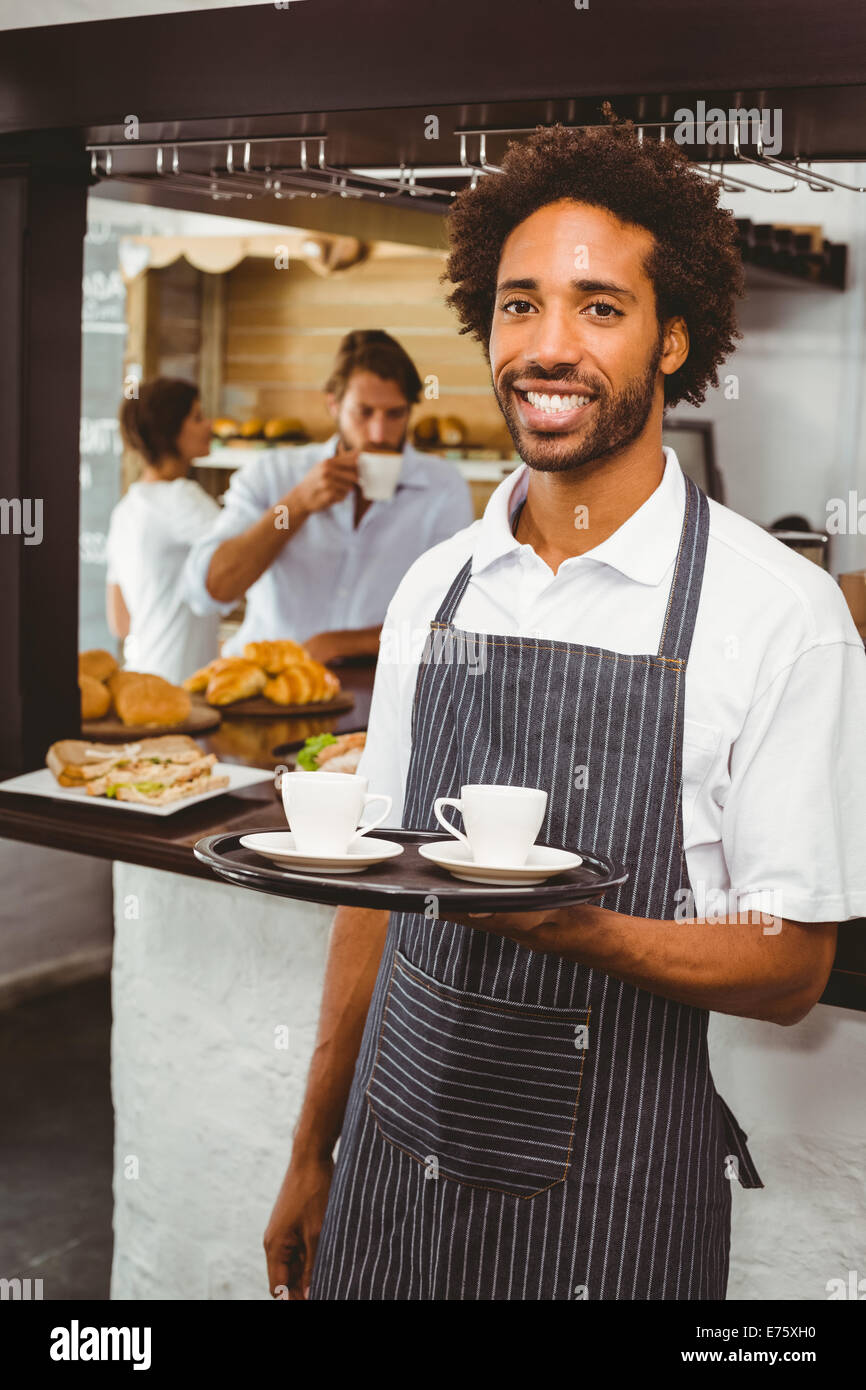Handsome waiter smiling at camera holding tray Stock Photo - Alamy