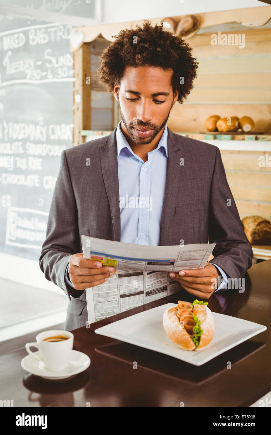 Businessman reading newspaper while having lunch Stock Photo - Alamy