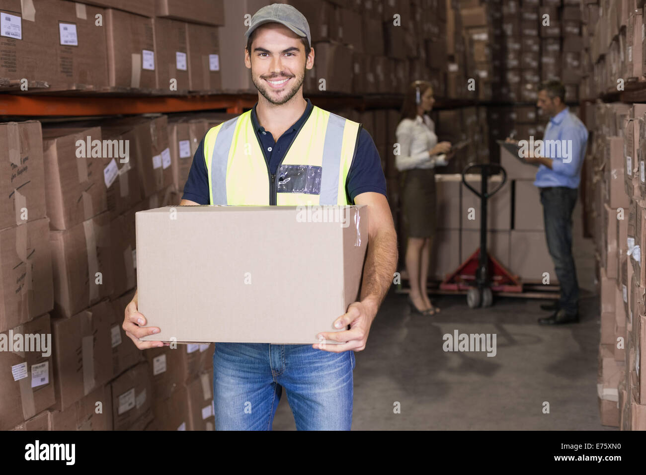 Warehouse worker smiling at camera carrying a box Stock Photo - Alamy
