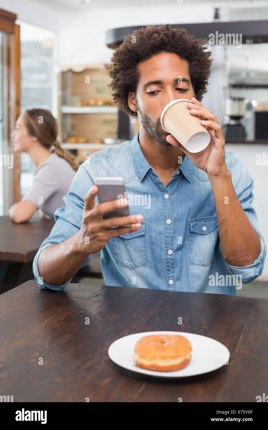 Handsome man sending a text drinking coffee Stock Photo - Alamy