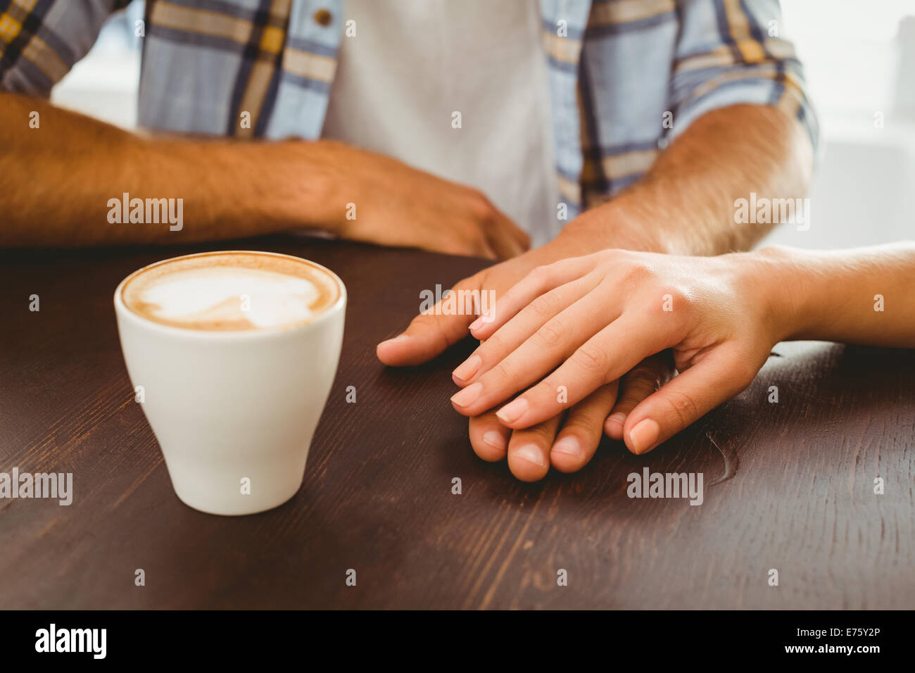 Couple enjoying a coffee holding hands Stock Photo - Alamy