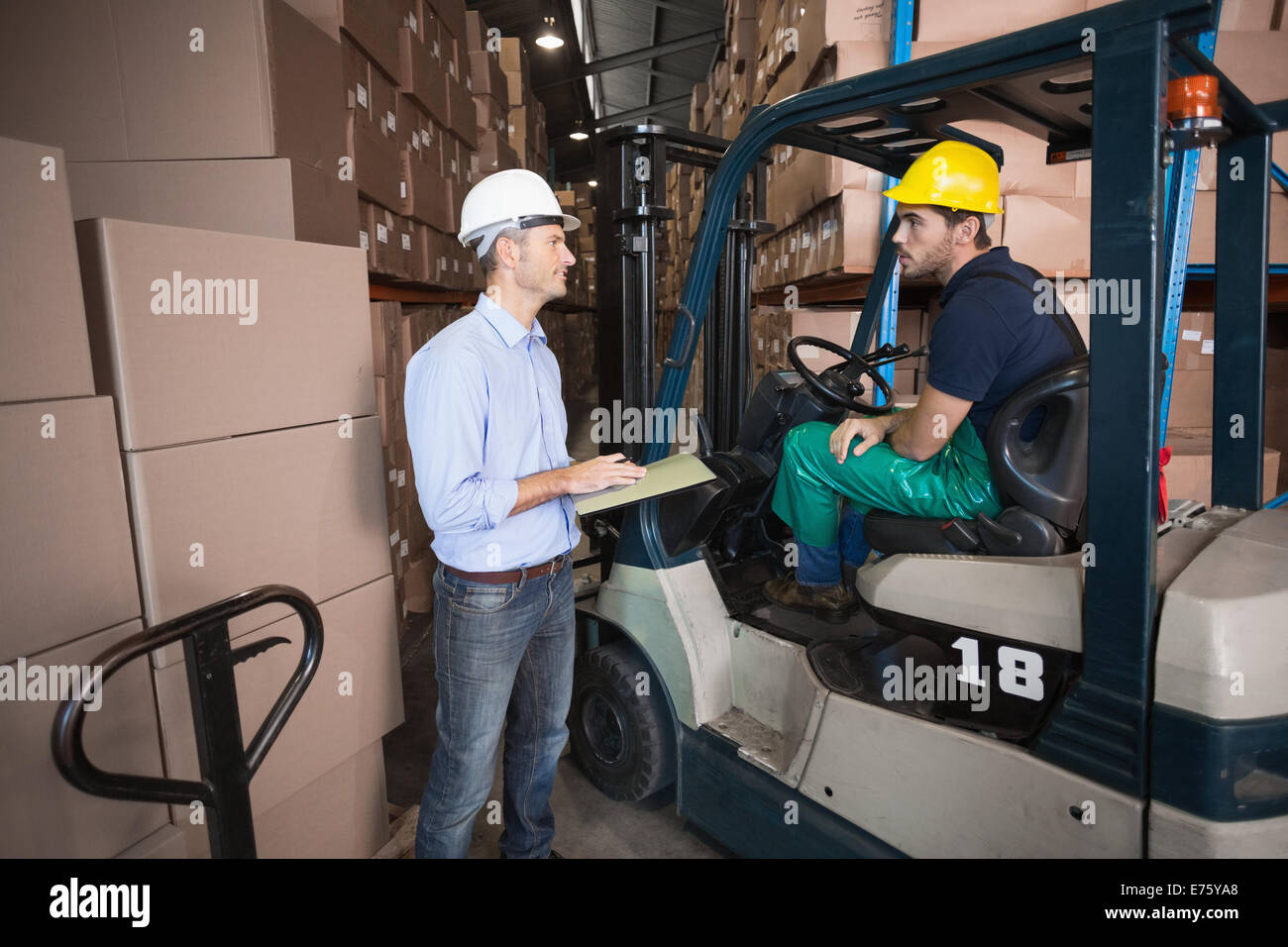 Warehouse manager talking with forklift driver Stock Photo - Alamy