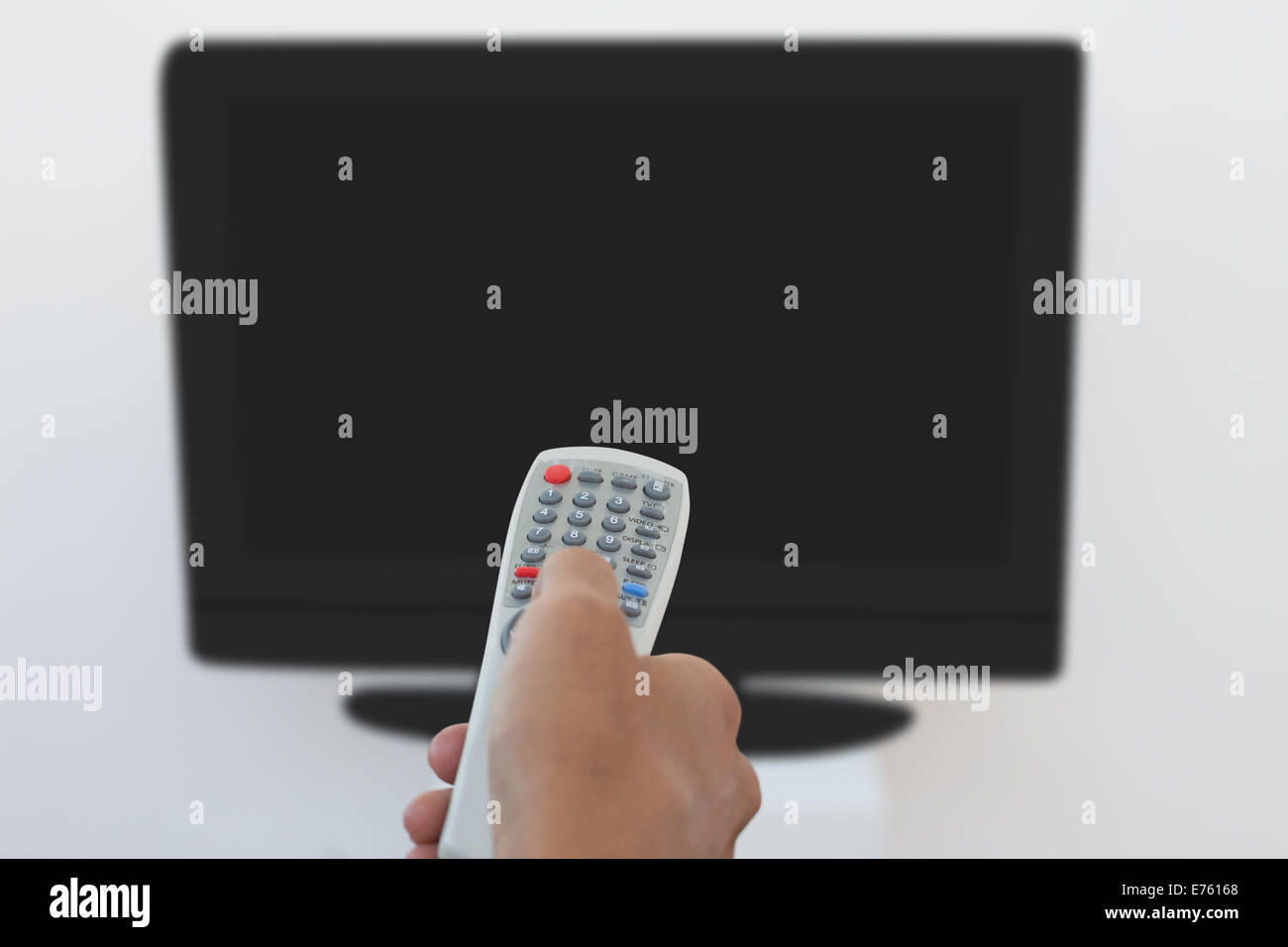 Hand holding remote and changing channel Stock Photo - Alamy