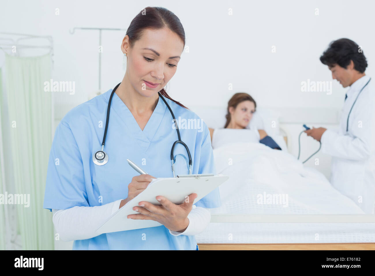Nurse writing on medical chart Stock Photo - Alamy