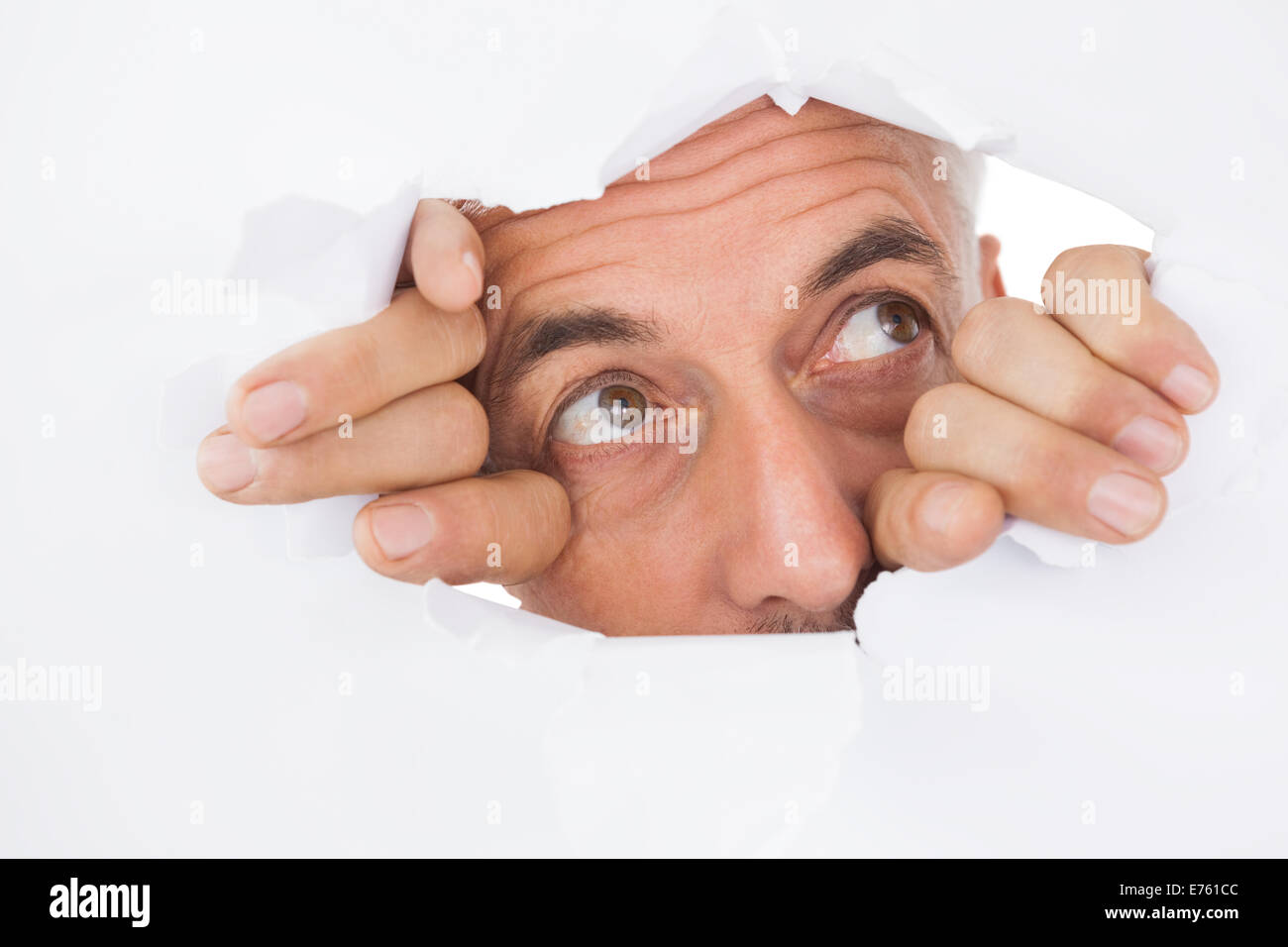 Man peeking through torn white surface Stock Photo - Alamy