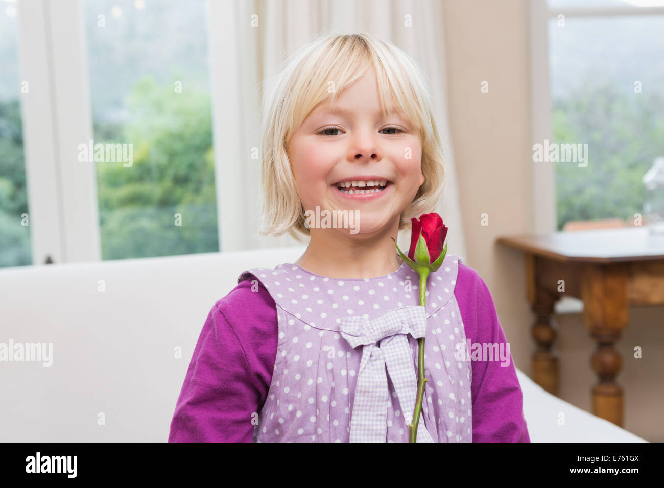 Cute little girl holding a red rose Stock Photo - Alamy