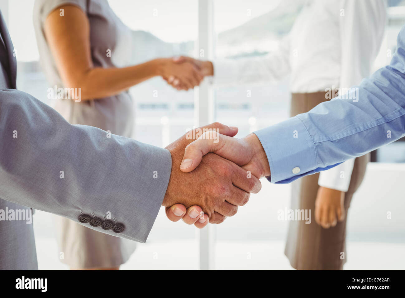 Two fellow employees shaking hands Stock Photo - Alamy